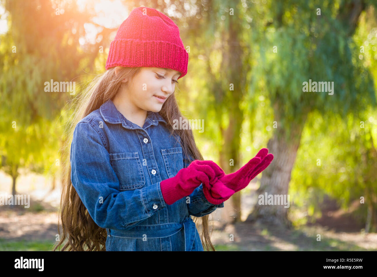 Cute Mixed Race Young Girl Wearing Red Knit Cap Putting On Mittens ...