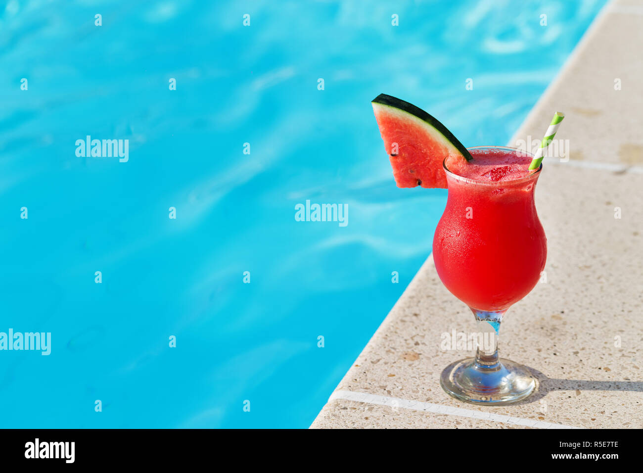 Glass of fresh watermelon smoothie juice drink on border of a swimming ...