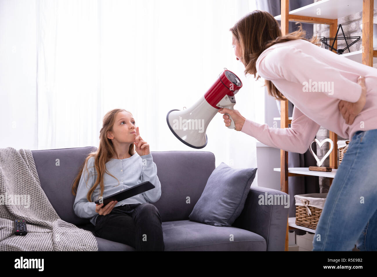 Mother Shouting Through Megaphone At Careless Girl Sitting On Sofa ...