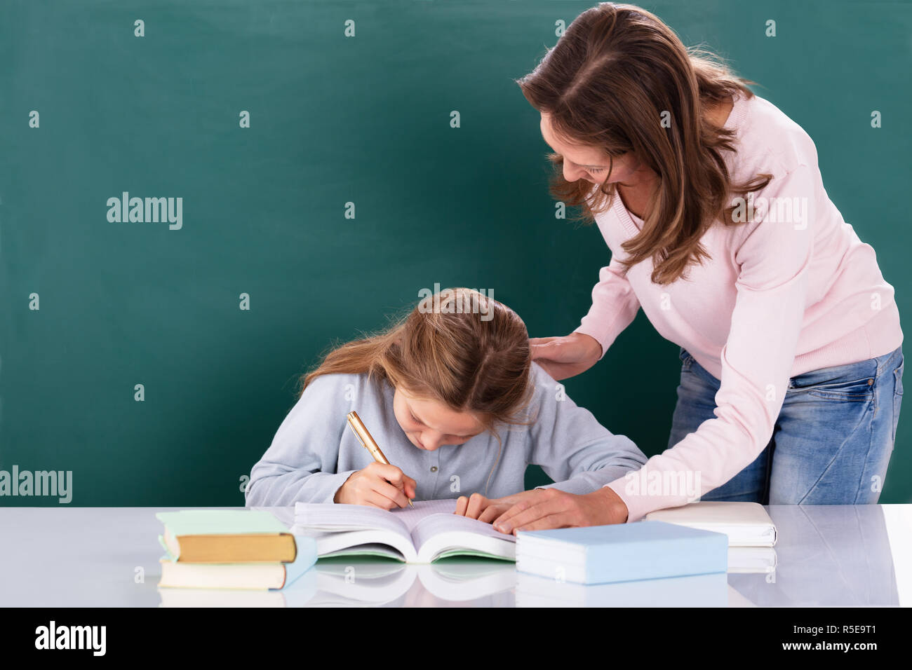 Female Teacher Helping Her Student Doing Class Work In Classroom Stock ...