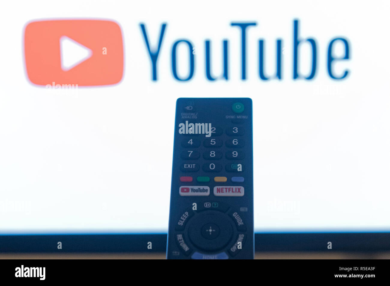 A man points a remote control at a smart television displaying the ...