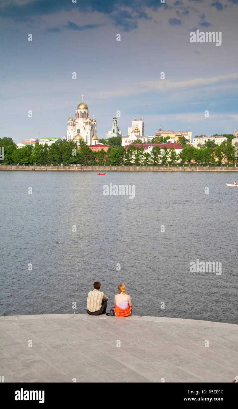 Russia, Ekaterinburg (Yekateringburg), Couple sitting on riverfront ...