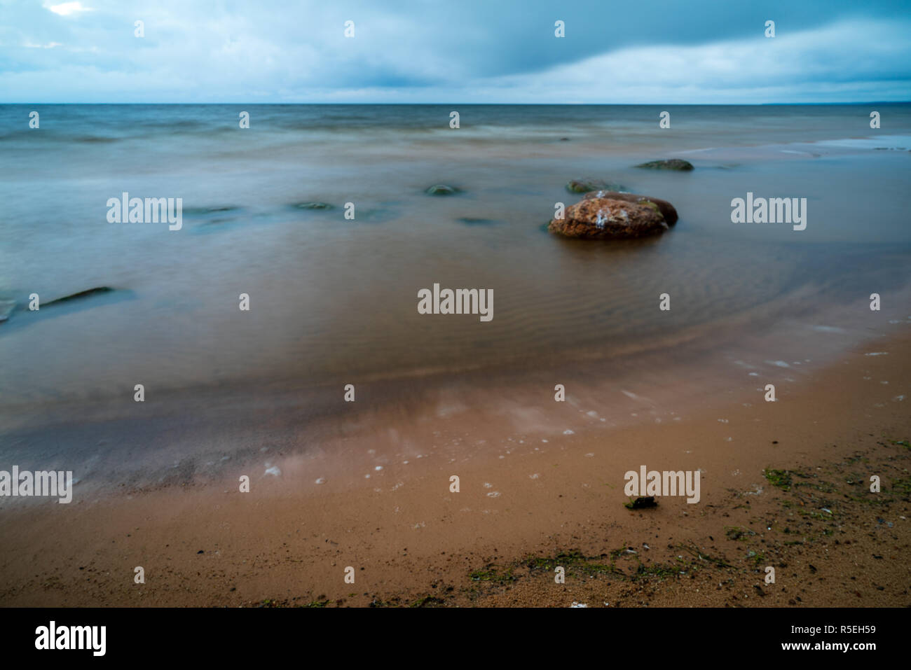 storm clouds forming over clear sea beach with rocks and clear sand ...