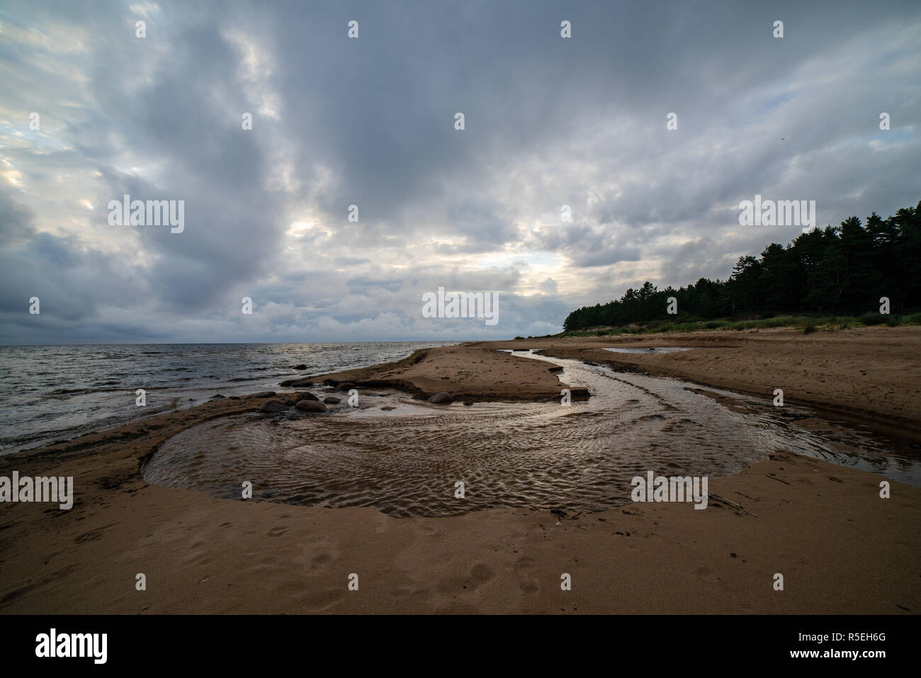 storm clouds forming over clear sea beach with rocks and clear sand ...