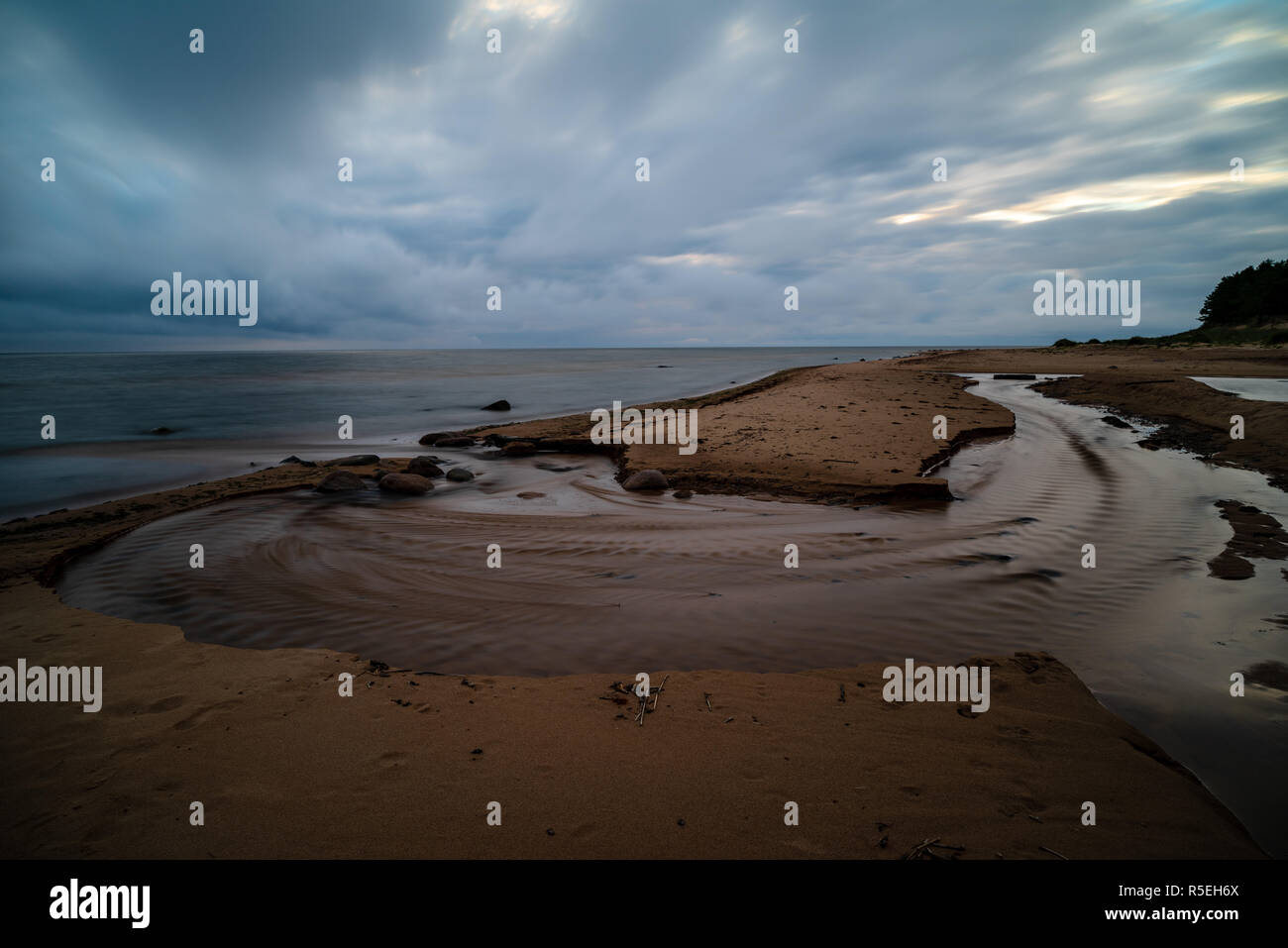 storm clouds forming over clear sea beach with rocks and clear sand ...