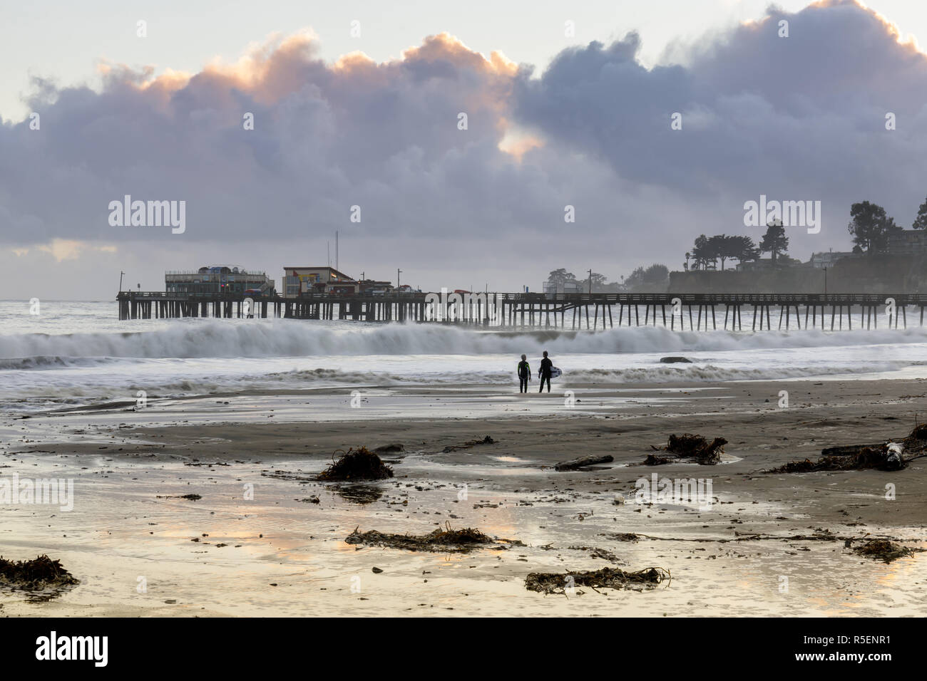 Capitola Beach and wharf in stormy clouds sunset and surfers silhouette ...