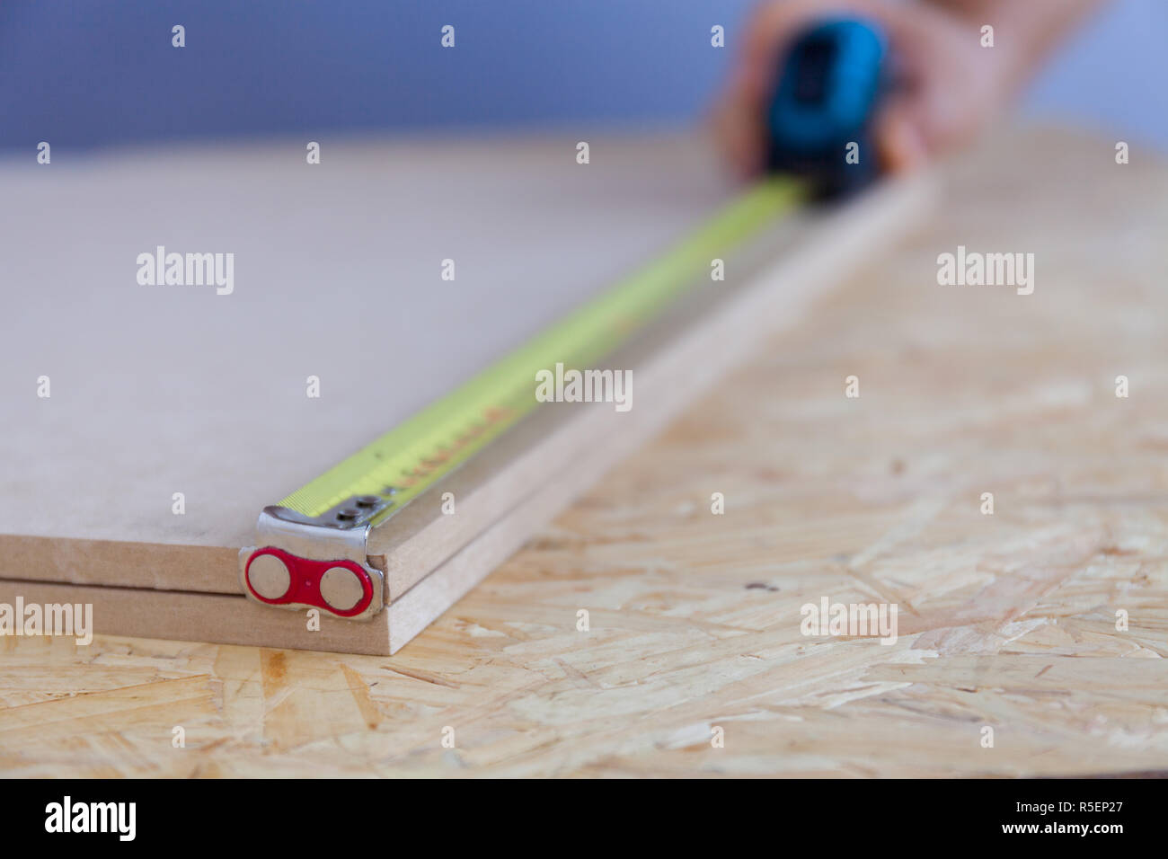 Close up view of a man's hand measuring wood with a tape. Handyman ...