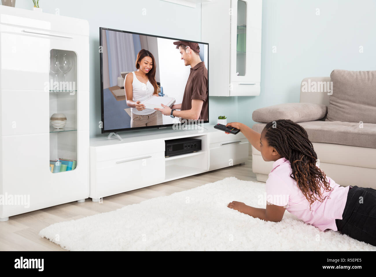 Girl Changing The Channel With Remote Control Stock Photo - Alamy