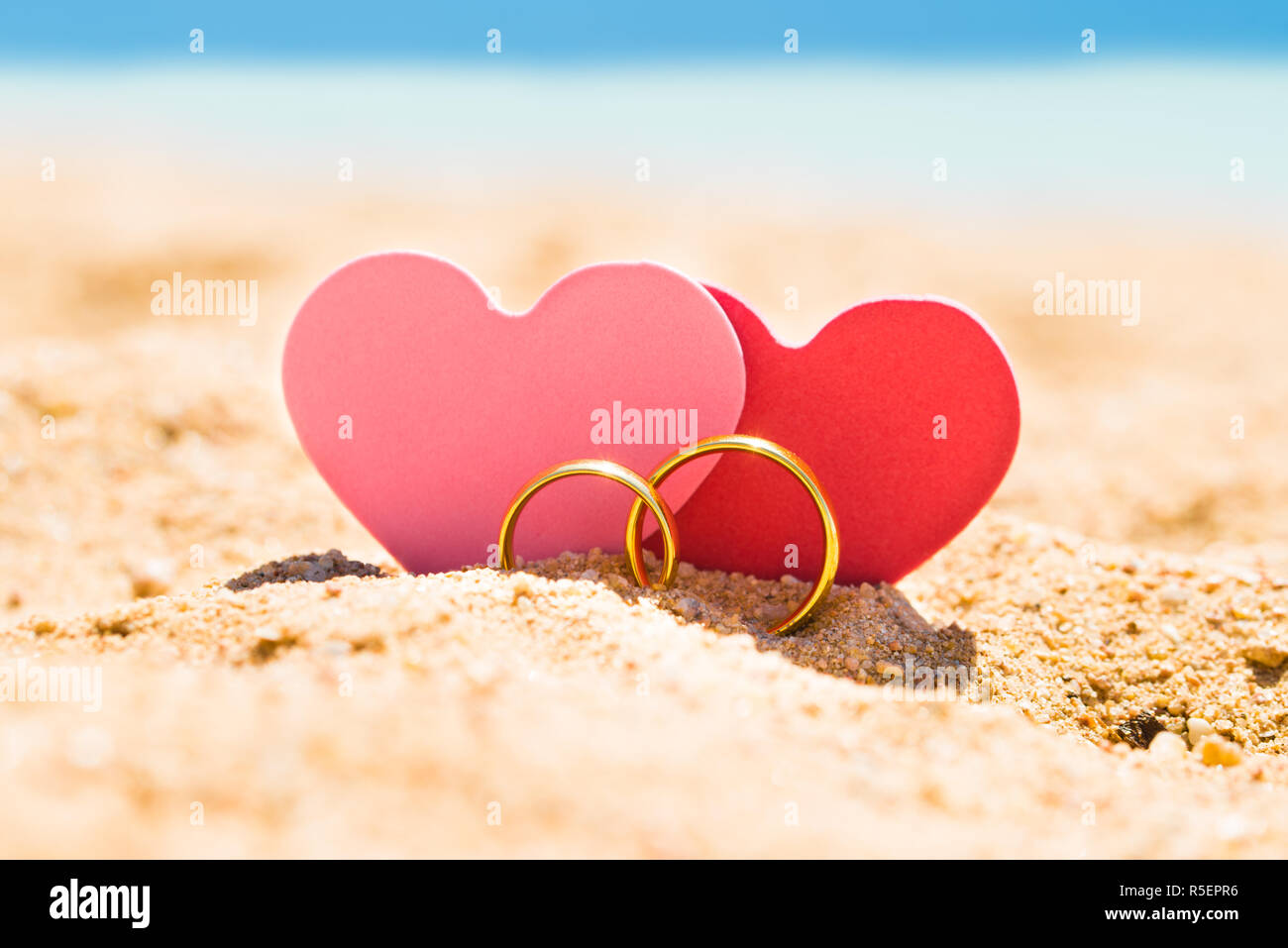 Two Heart Shapes With Golden Rings On Sand Stock Photo - Alamy