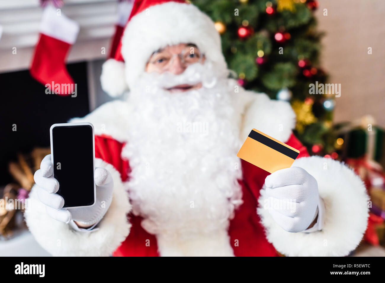 santa claus holding credit card and showing smartphone with blank ...
