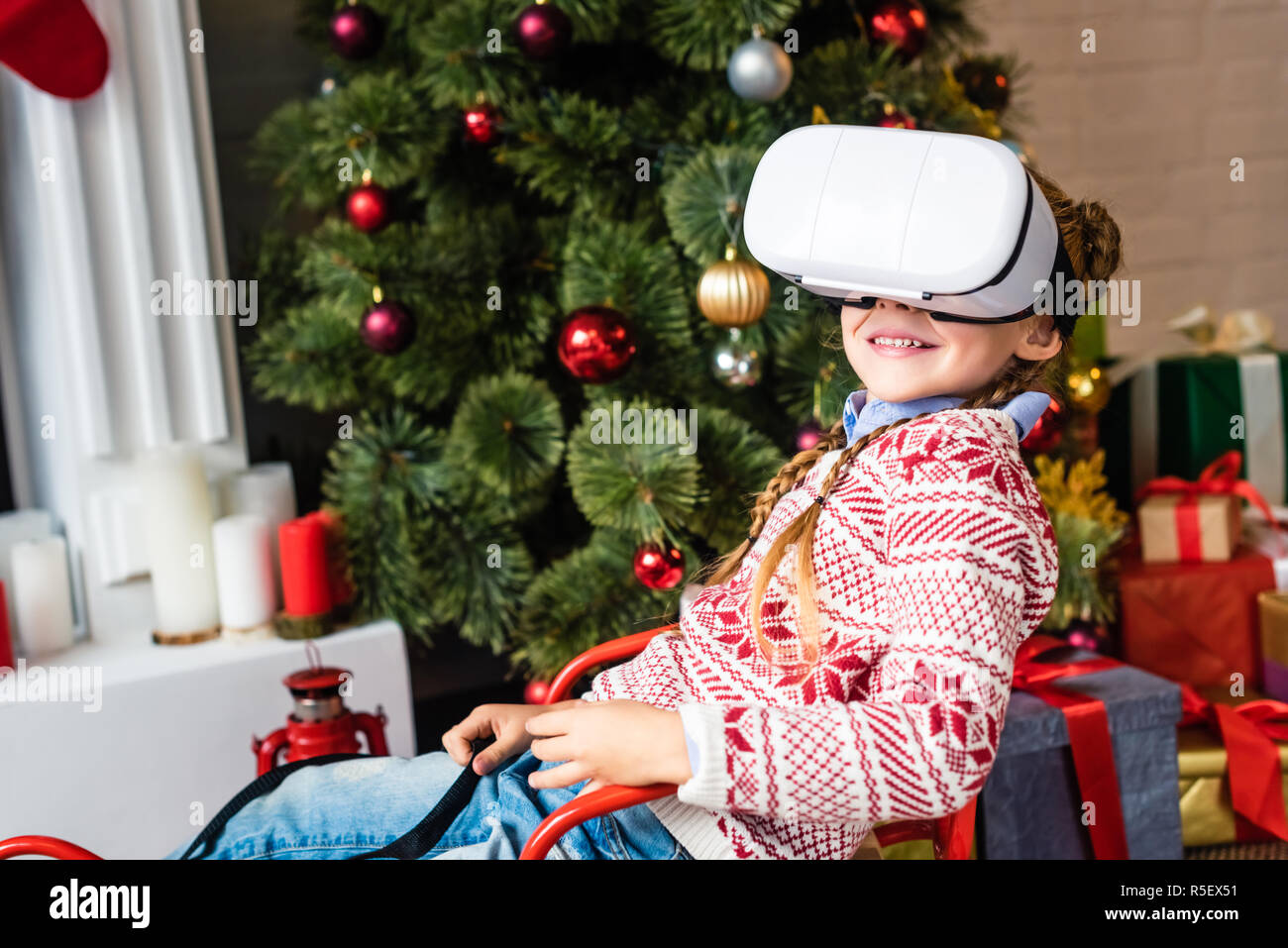cute smiling child sitting in sled and using virtual reality headset at ...