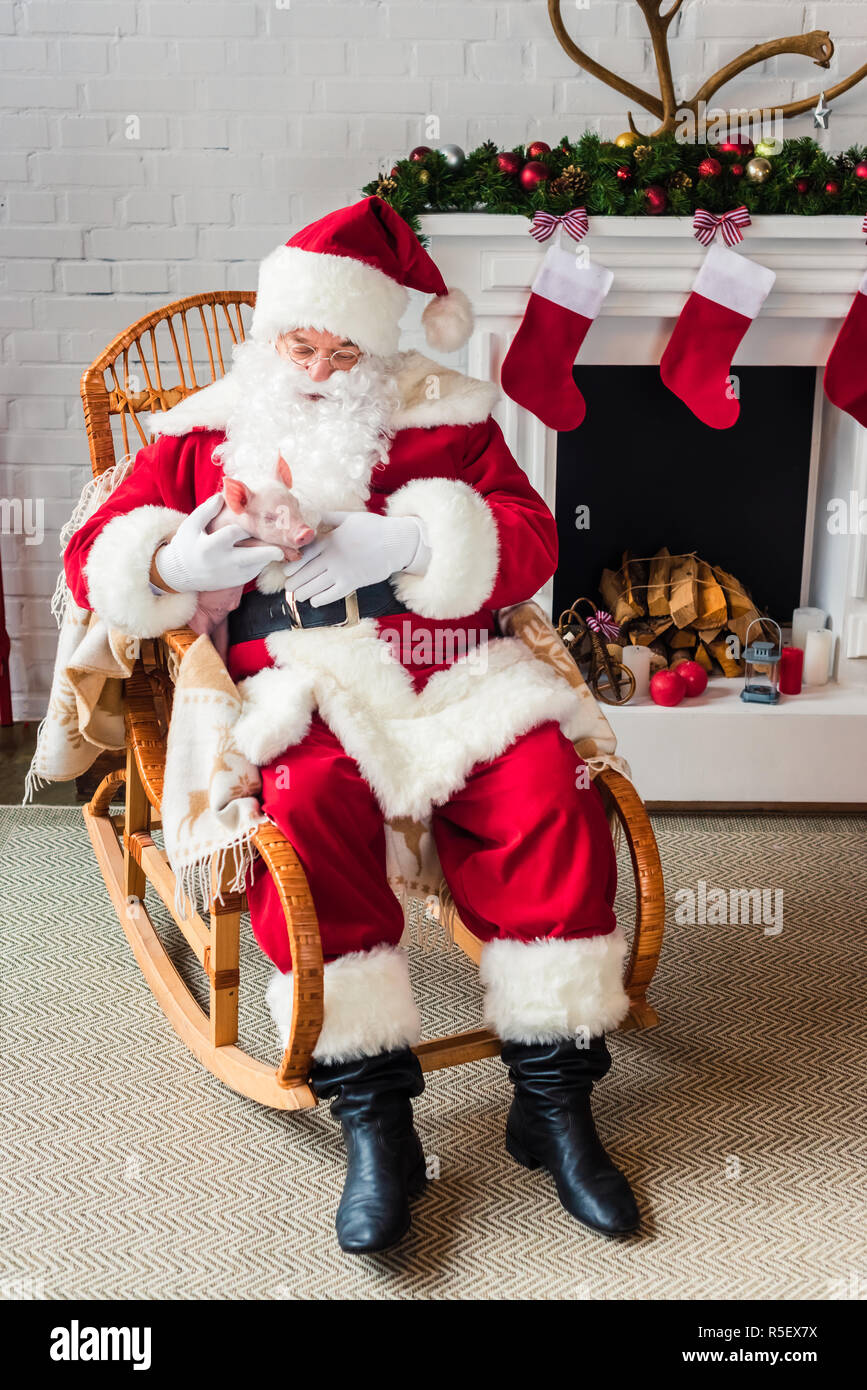 high angle view of santa claus holding pig and sitting in rocking chair ...