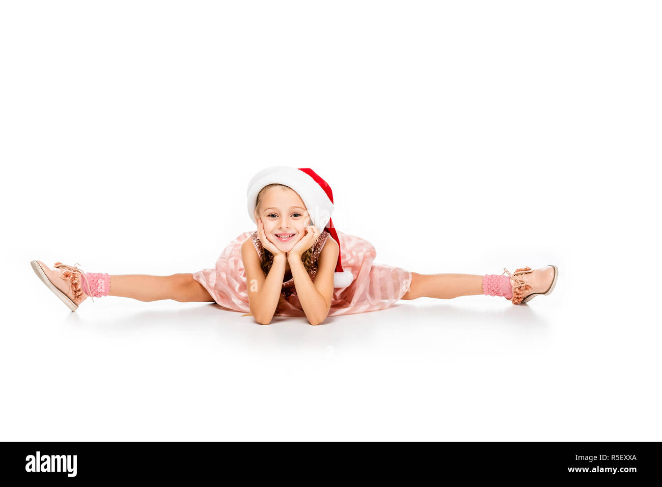 adorable little child in santa hat sitting splits on floor and looking ...