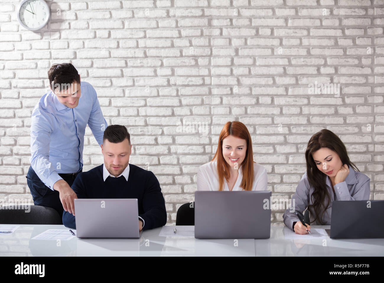 Businessman Assisting People At Computer Stock Photo - Alamy