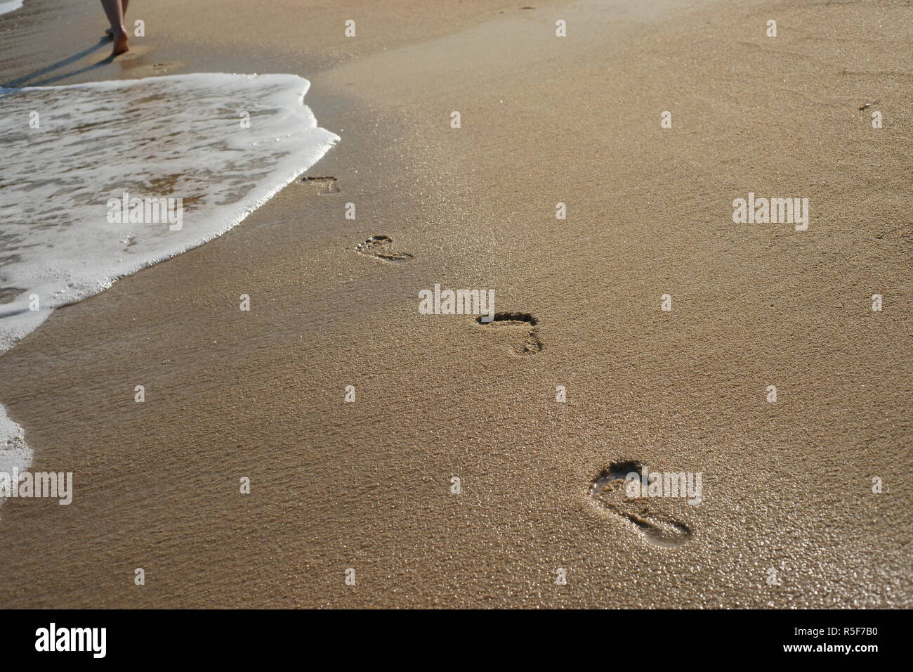 Beach wave and footsteps on the beach Stock Photo - Alamy