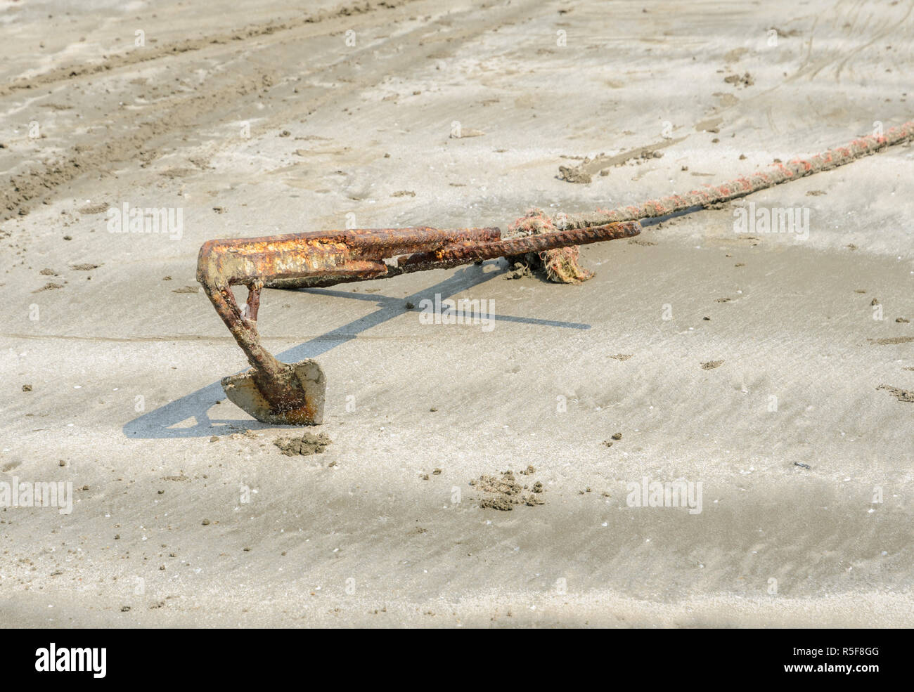 Small rusty boat anchor in the sand on beach Stock Photo - Alamy