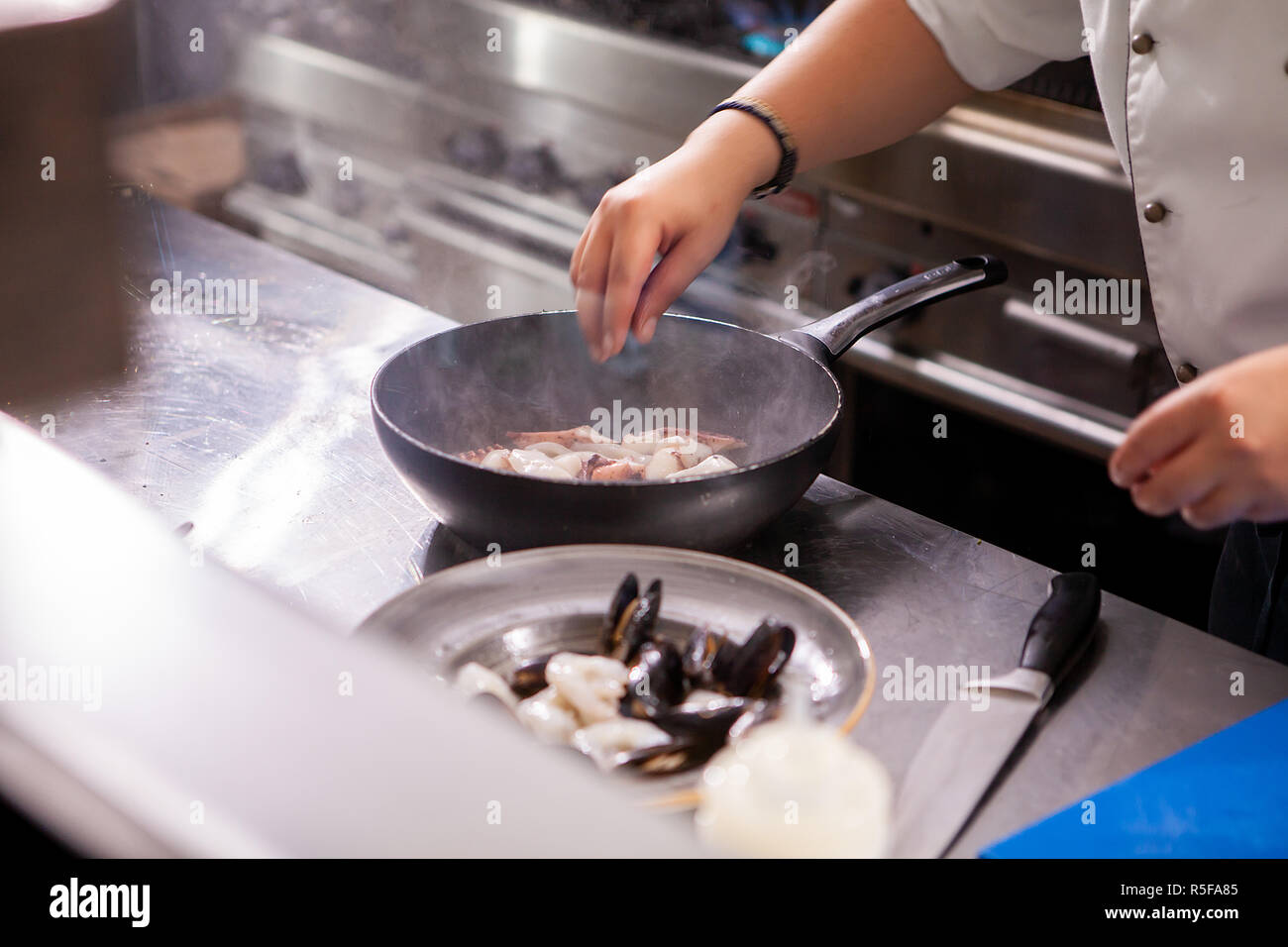 Male cook fries seafood at stove in kitchen restaurant Stock Photo - Alamy
