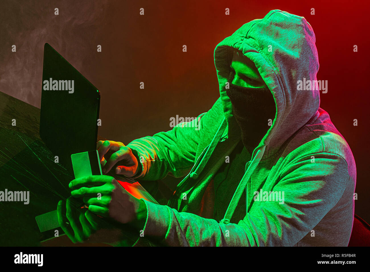 Hooded computer hacker stealing information with laptop Stock Photo - Alamy