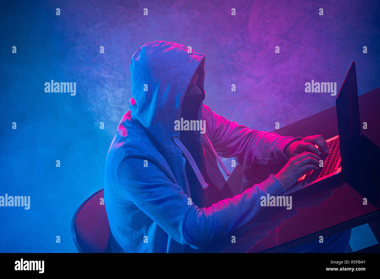 Hooded computer hacker stealing information with laptop Stock Photo - Alamy