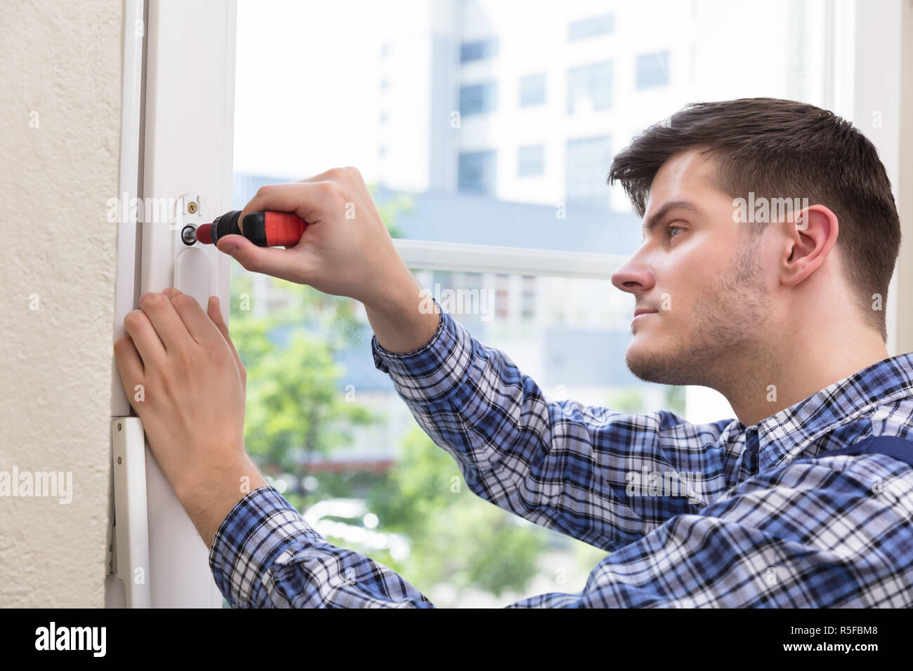 Handyman Fixing Window With Screwdriver Stock Photo - Alamy