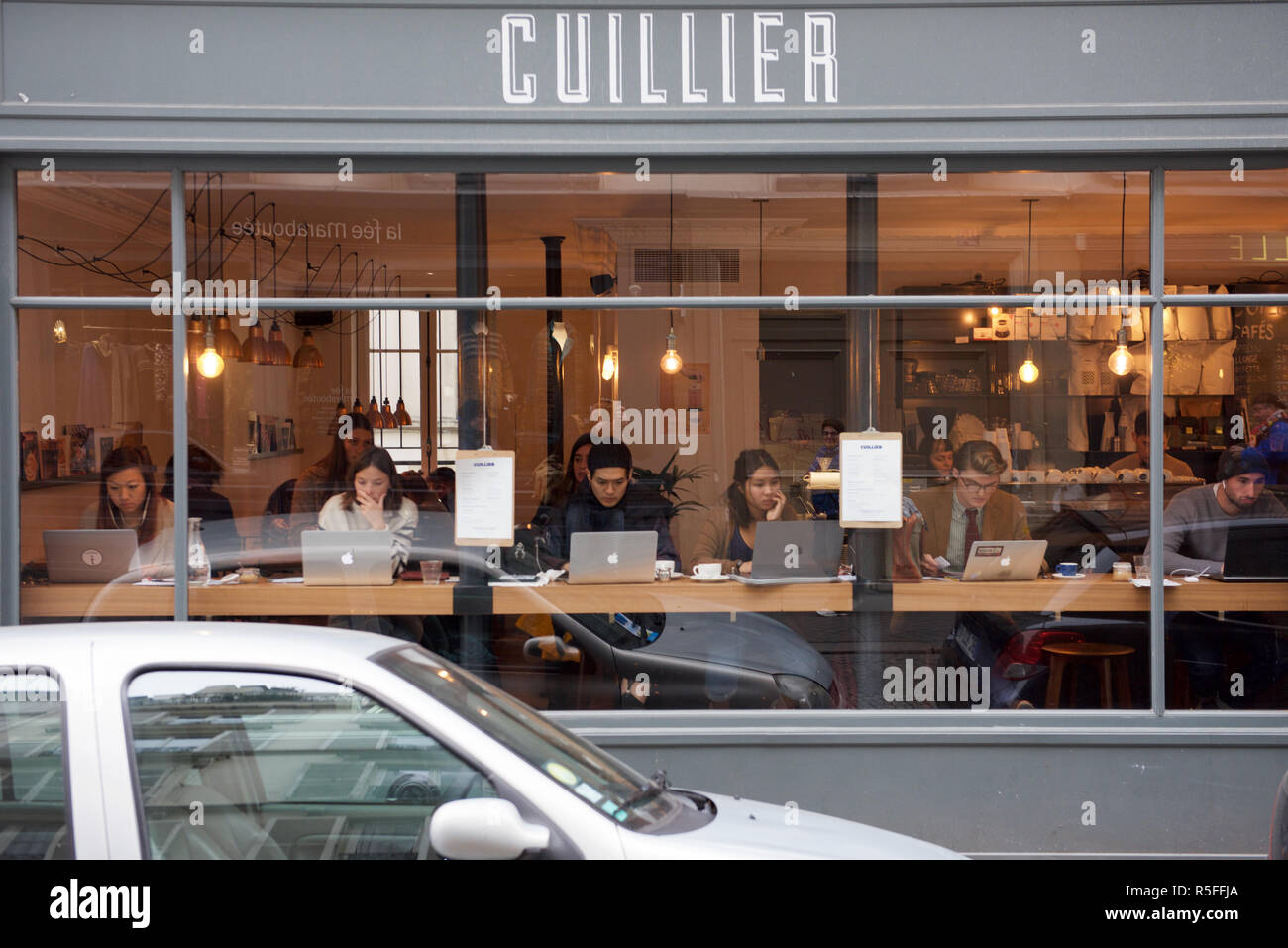 People using laptops in the window of a street cafe in Paris, France ...