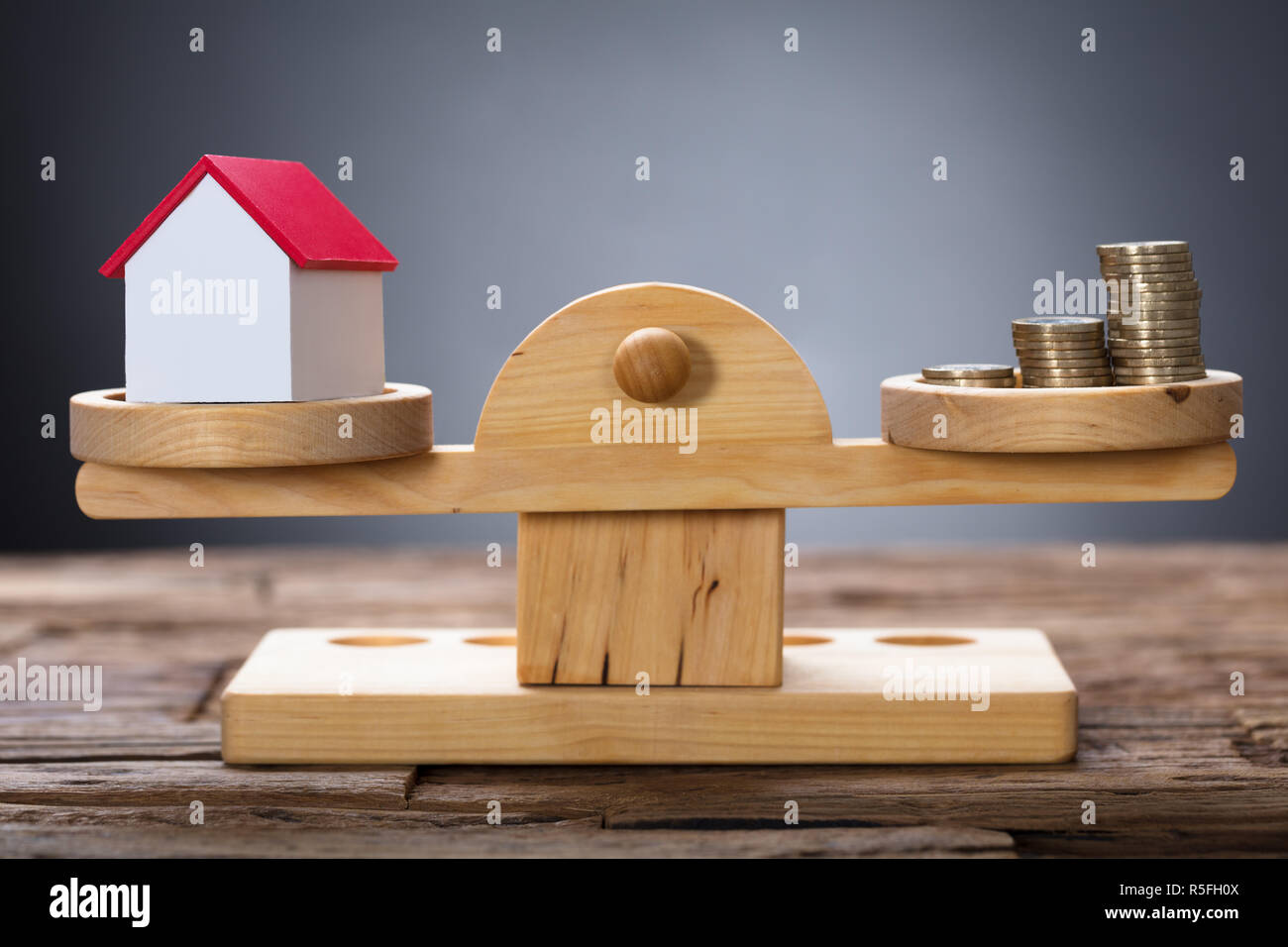 Model Home And Coins Balancing On Wooden Weighing Scale Stock Photo - Alamy
