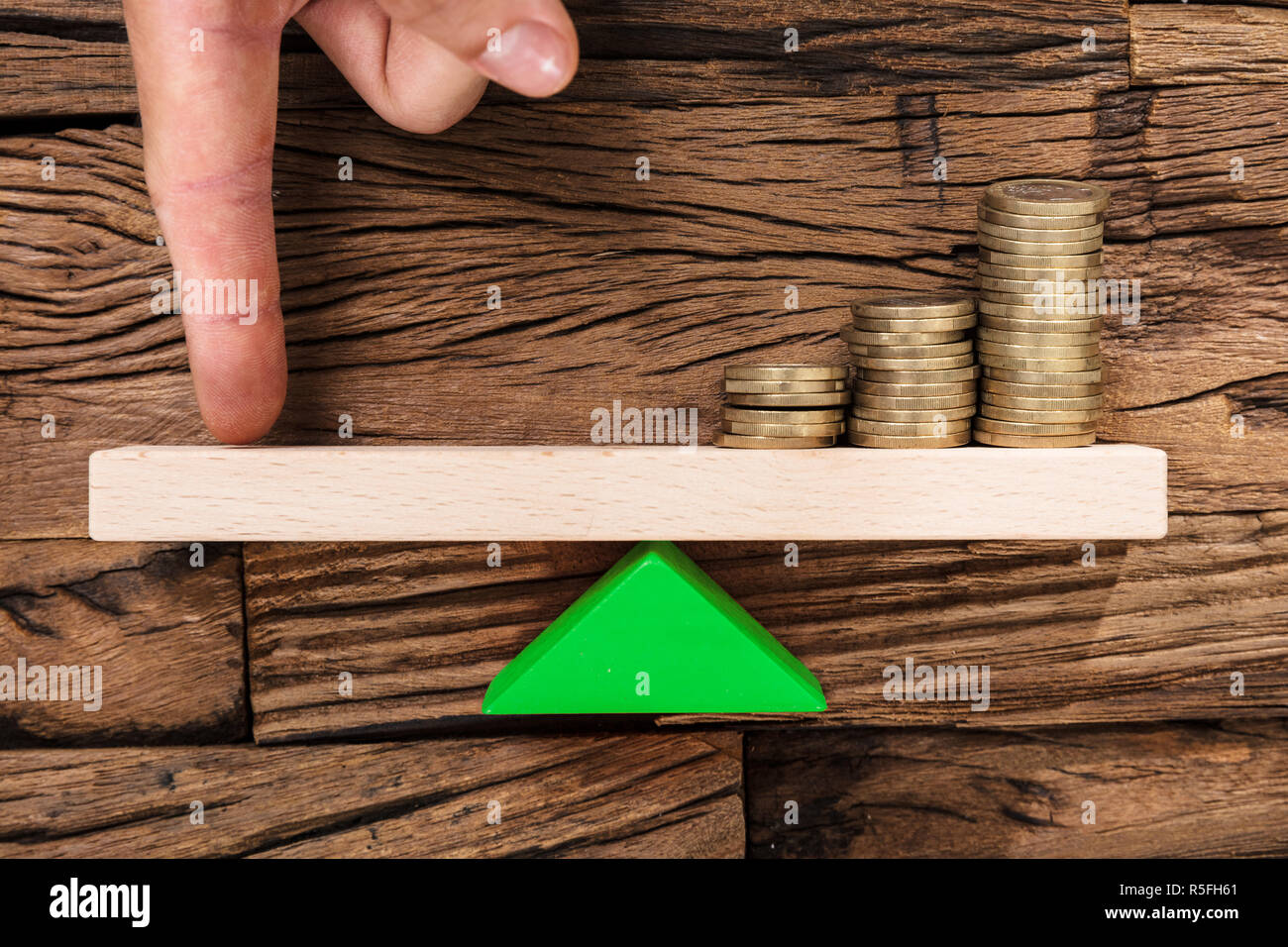 Finger Balancing Stacked Coins On Seesaw Stock Photo - Alamy