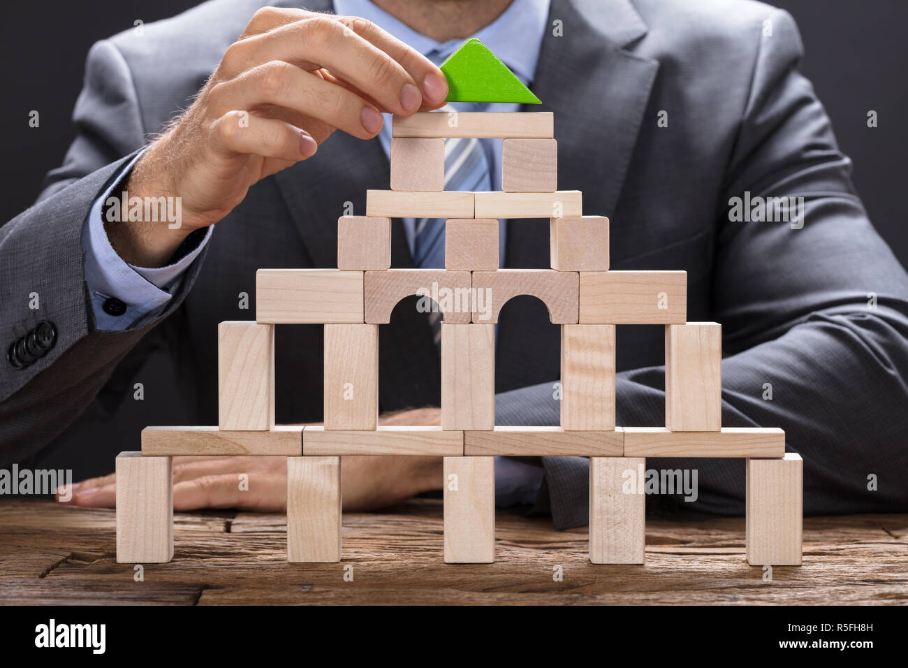 Businessman Making Building With Wooden Blocks Stock Photo - Alamy
