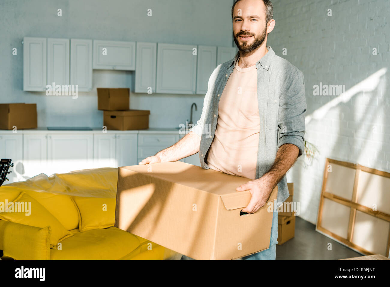 handsome man carrying cardboard box and packing for new house, moving ...
