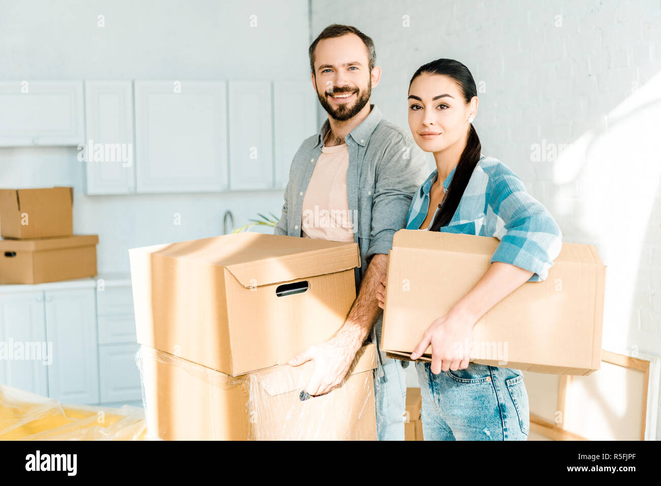 husband and wife carrying cardboard boxes and packing for new house ...
