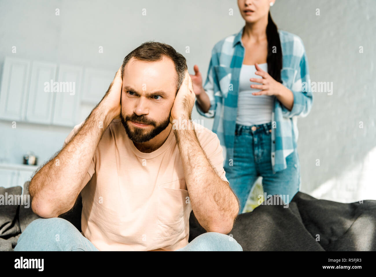 angry husband on foreground covering ears with hands and having ...