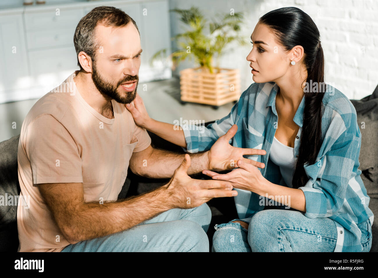 Couple Having Argument And Wife Trying To Calm Down Angry Husband At