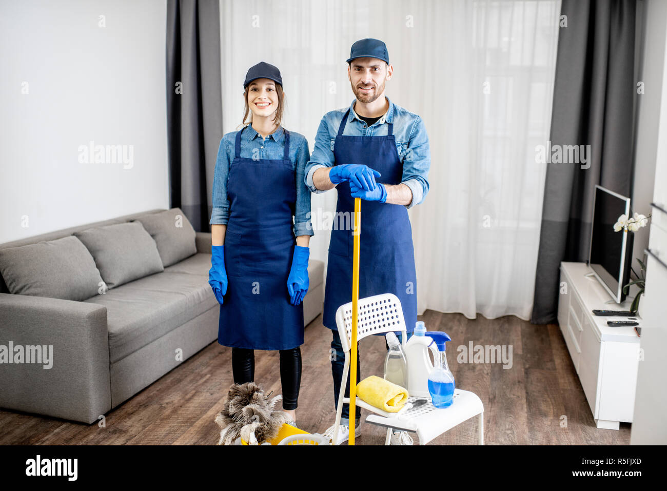 Portrait of a young couple as a professional cleaners in blue uniform ...