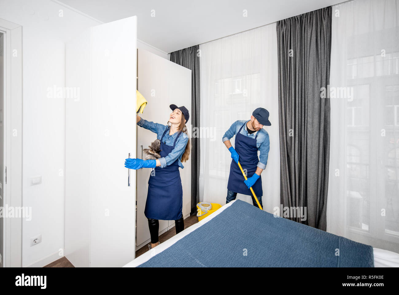 Professional cleaners in blue uniform washing floor and wiping ...