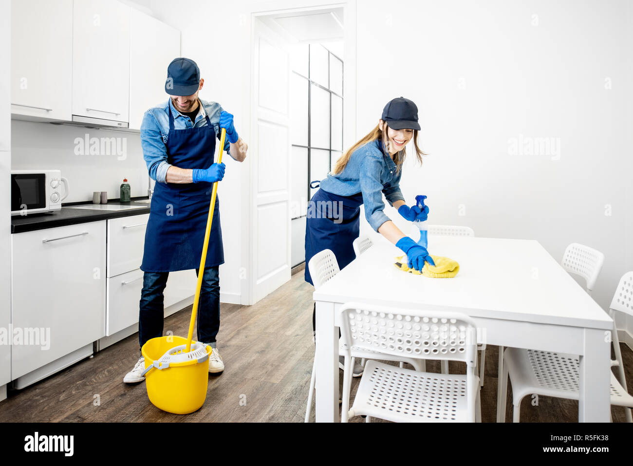 Man and woman as a professional cleaners in uniform washing floor and ...