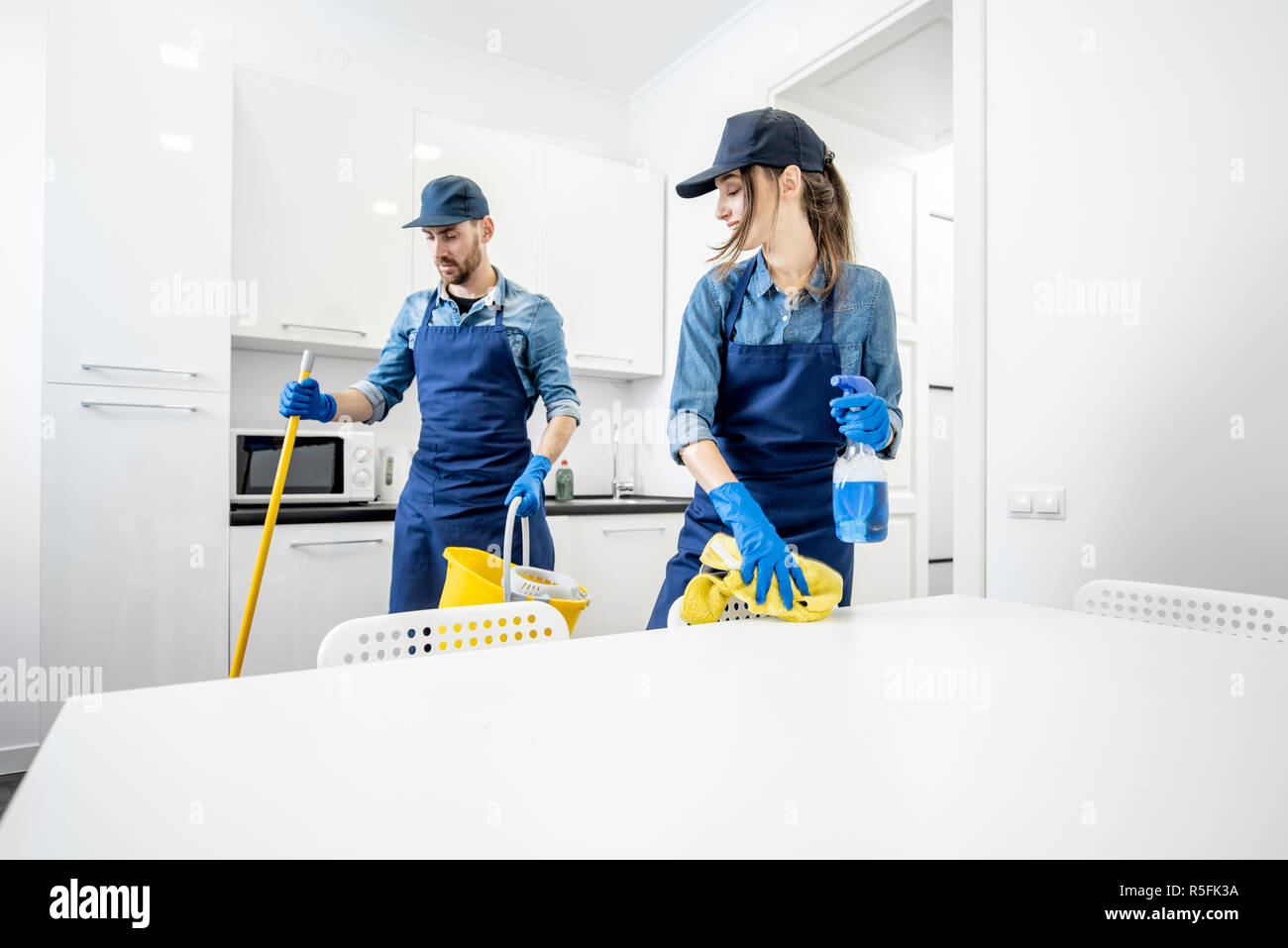 Man and woman as a professional cleaners in uniform washing floor and ...