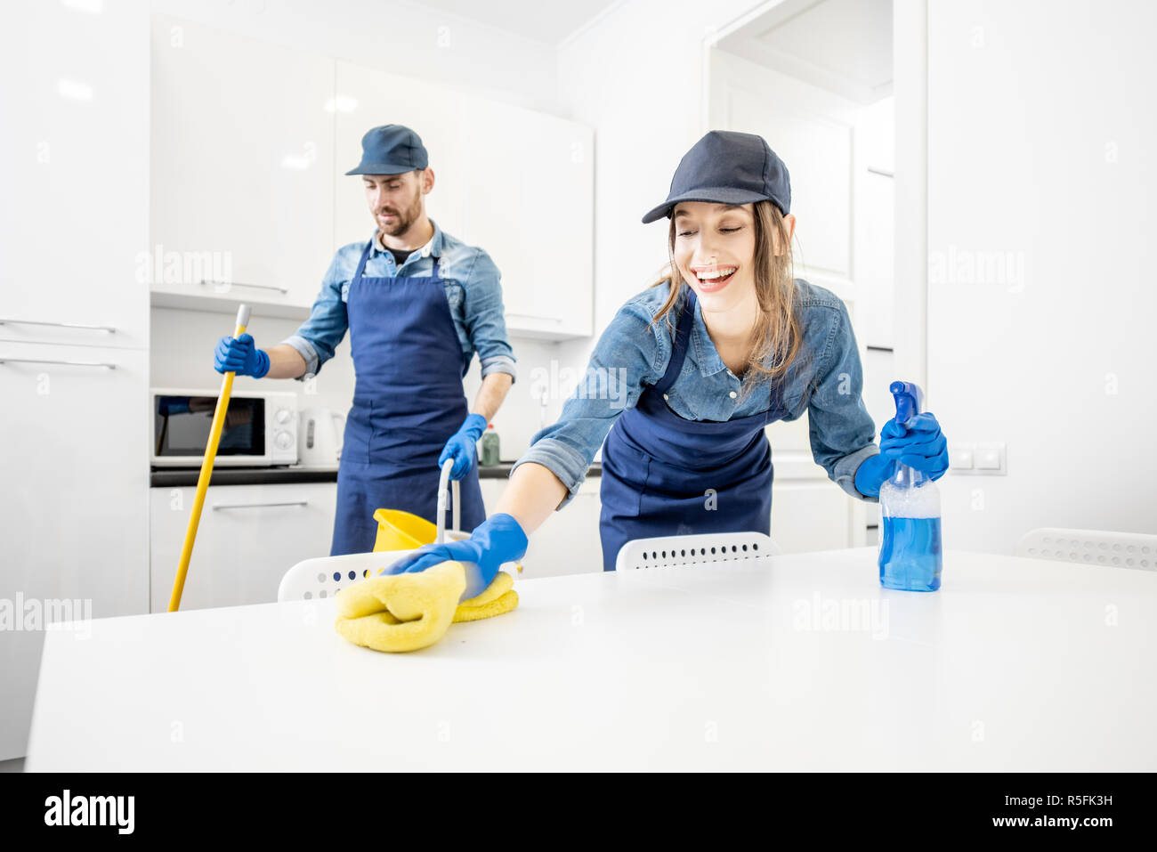 Man and woman as a professional cleaners in uniform washing floor and ...