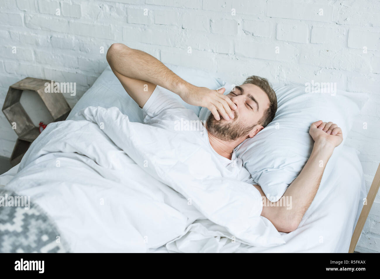 handsome young man yawning and stretching while lying in bed Stock ...