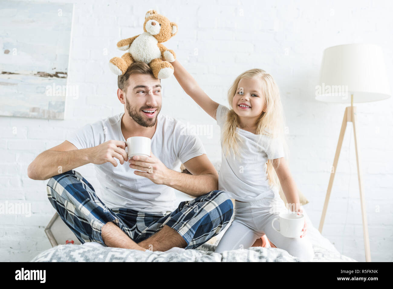 cute little daughter playing with teddy bear and smiling at camera ...