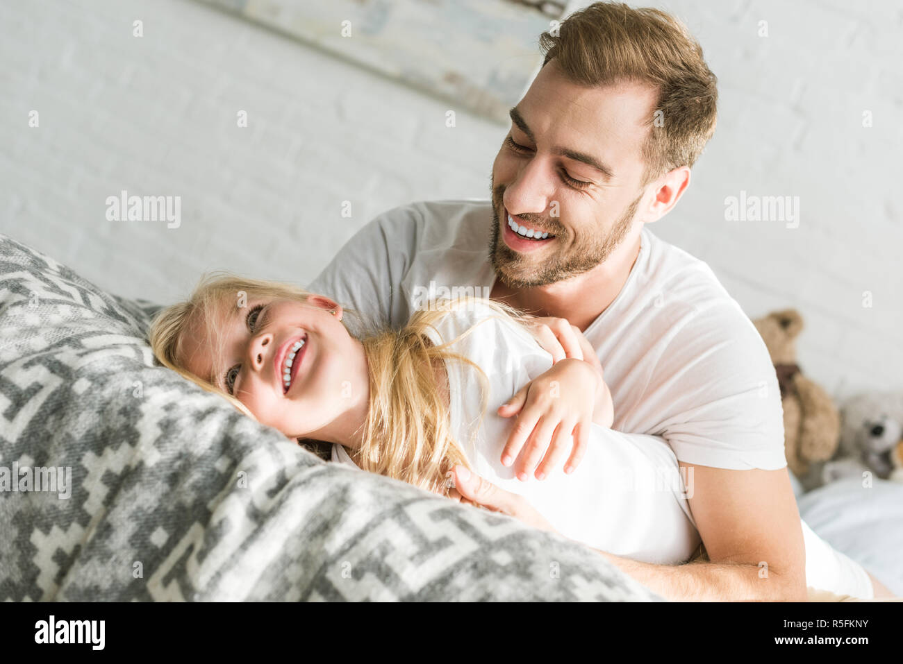 happy father hugging adorable little daughter on bed Stock Photo - Alamy