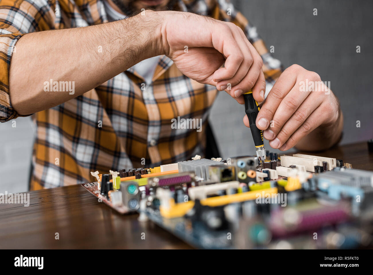 cropped shot of computer engineer repairing motherboard with ...