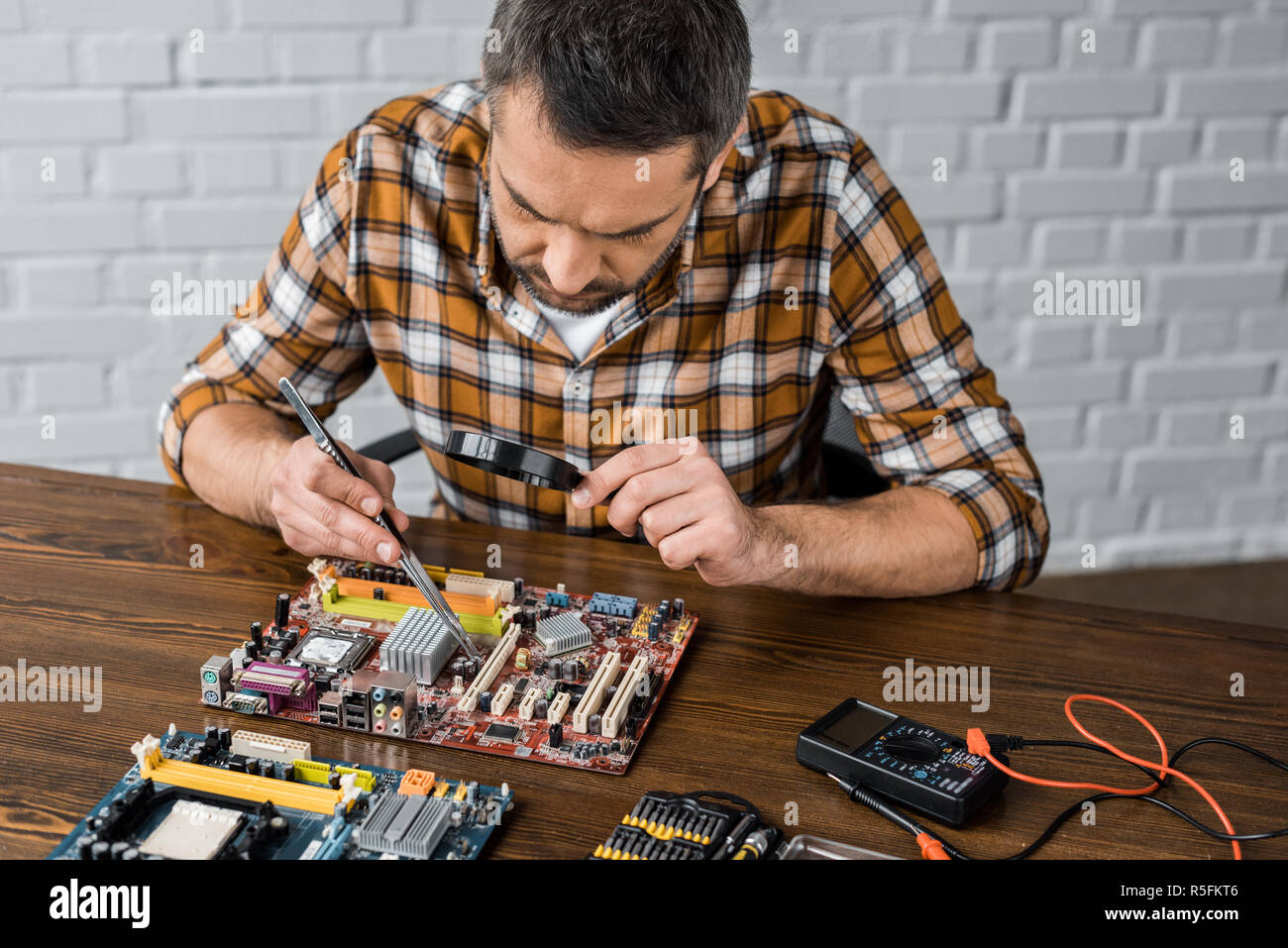 concentrated electronics engineer with tweezers and magnifying glass ...