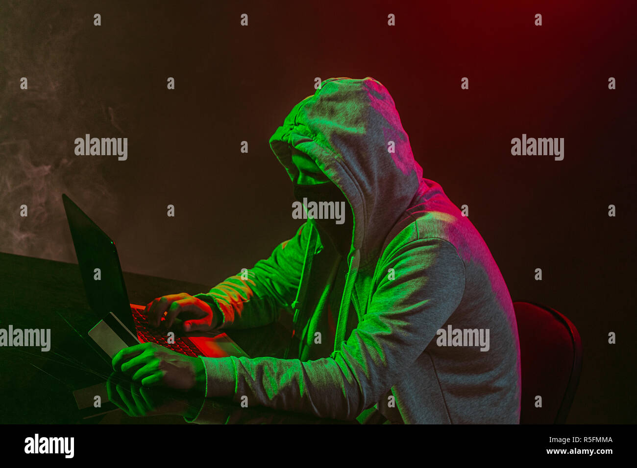 Hooded computer hacker stealing information with laptop Stock Photo - Alamy