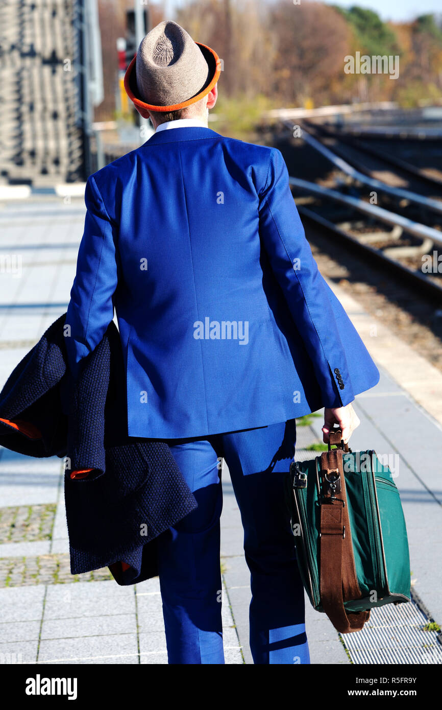businessman with hat and blue suit walking at train station Stock Photo ...