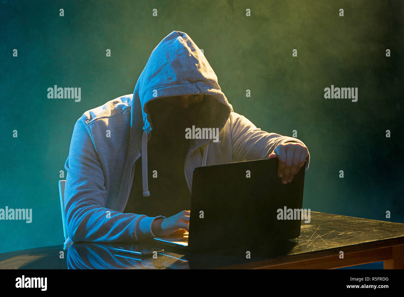 Hooded computer hacker stealing information with laptop Stock Photo - Alamy