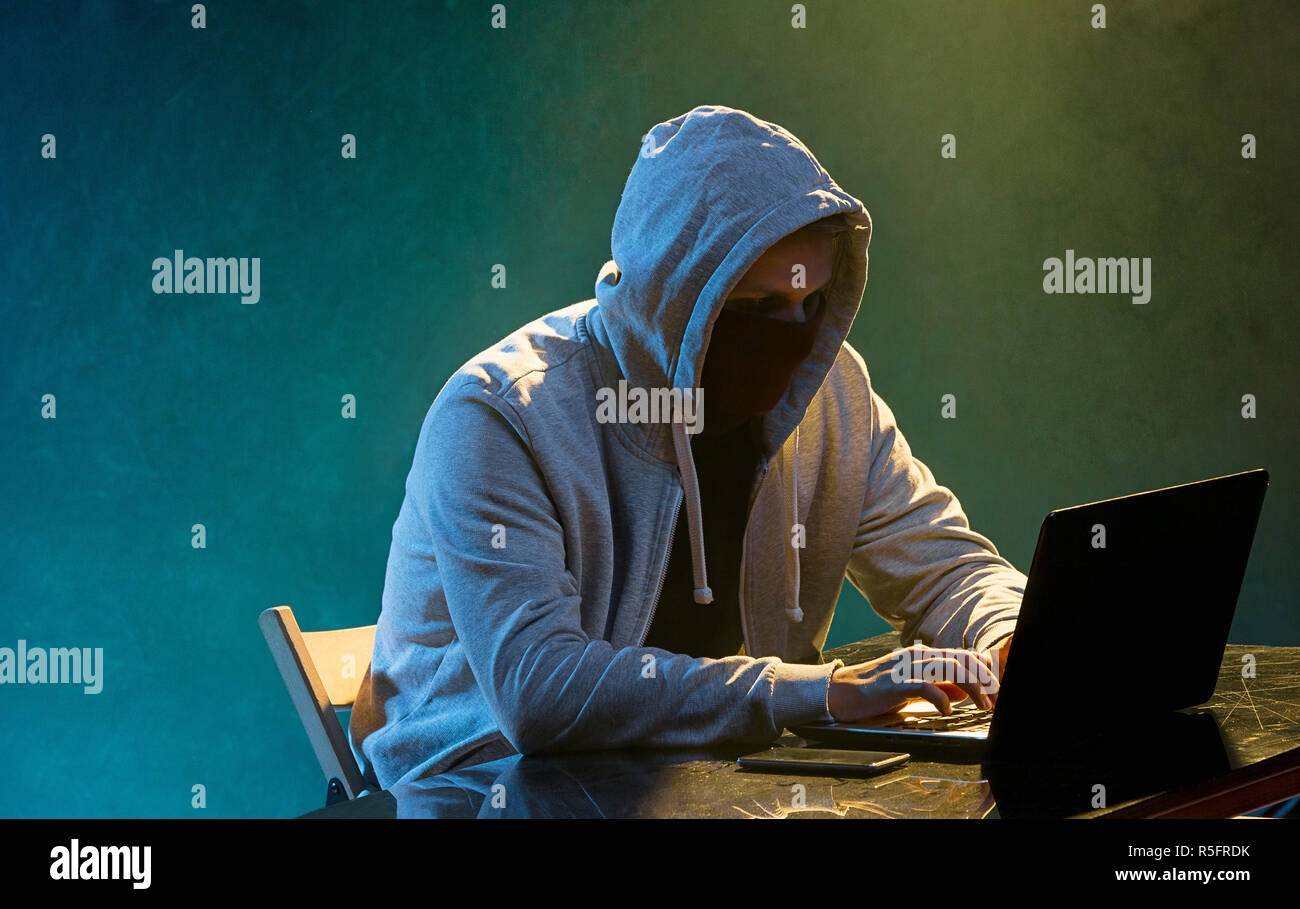 Hooded computer hacker stealing information with laptop Stock Photo - Alamy