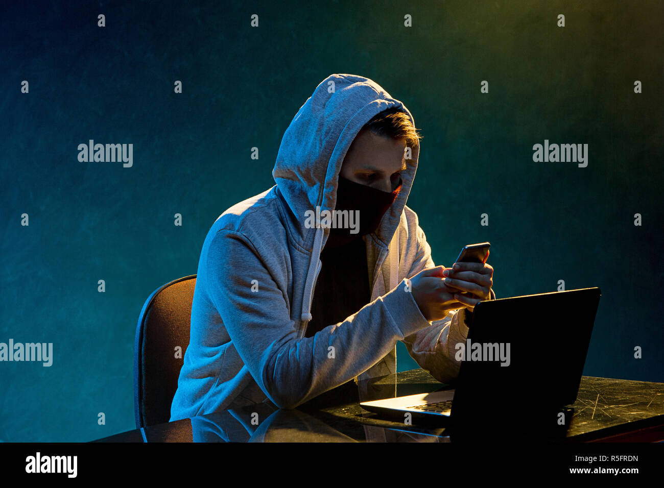Hooded computer hacker stealing information with laptop Stock Photo - Alamy