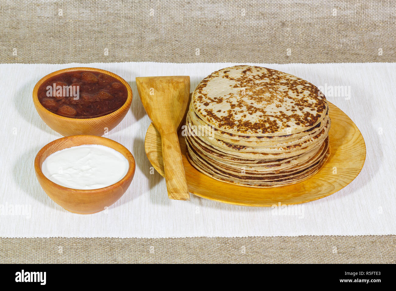 A stack of pancakes with sour cream and jam on the tablecloth Stock ...