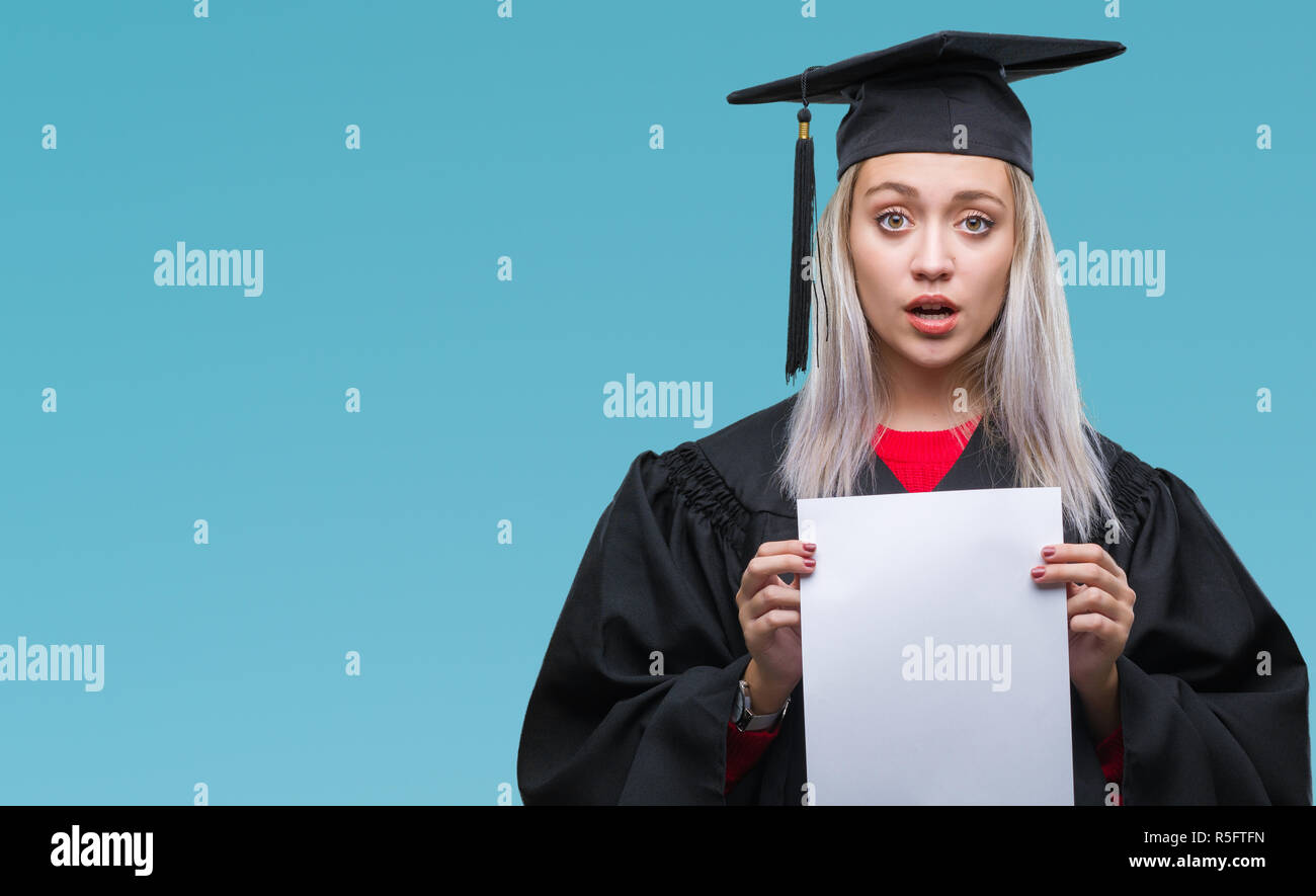 Young blonde woman wearing graduate uniform holding degree over ...