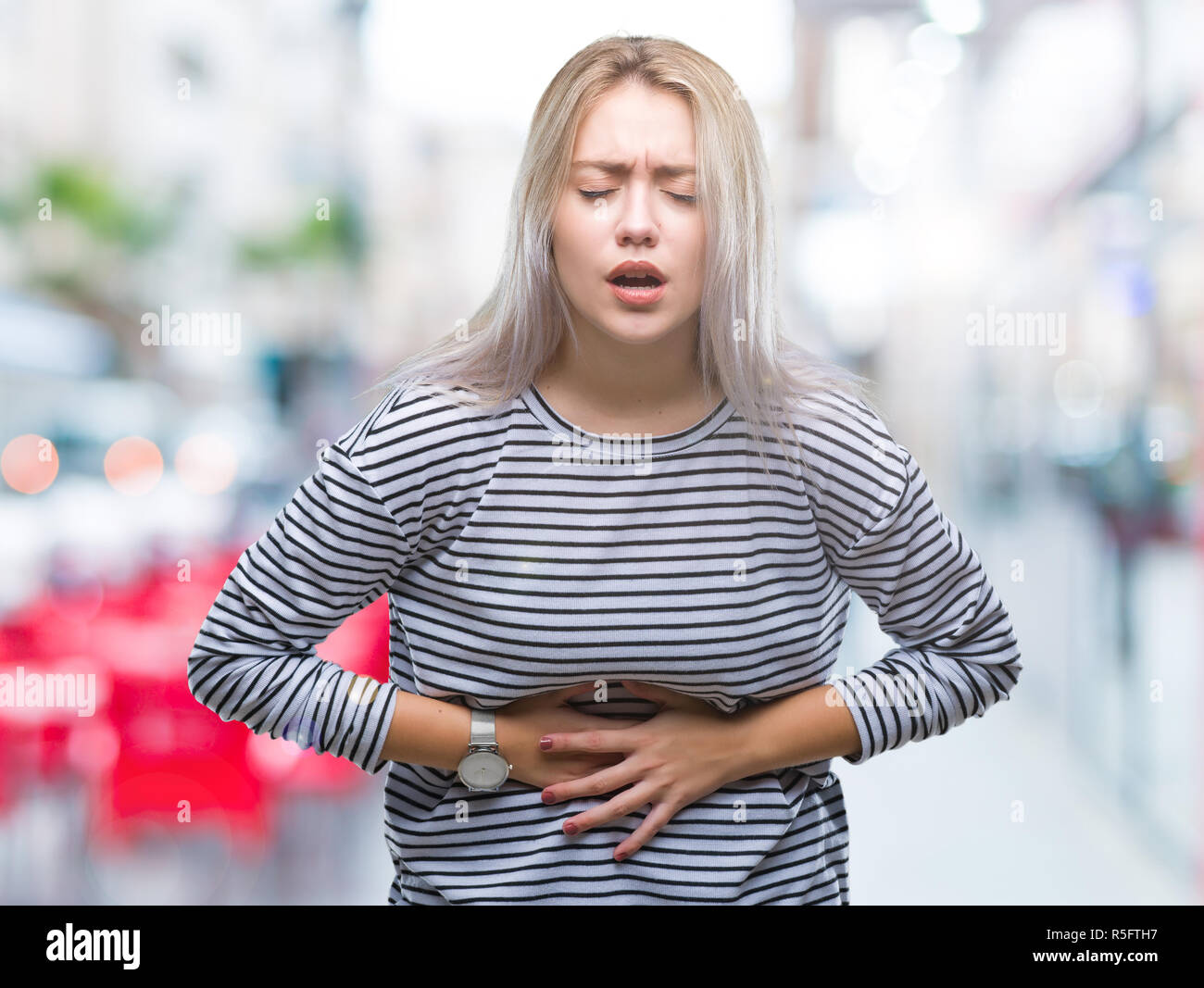 Young blonde woman over isolated background with hand on stomach ...